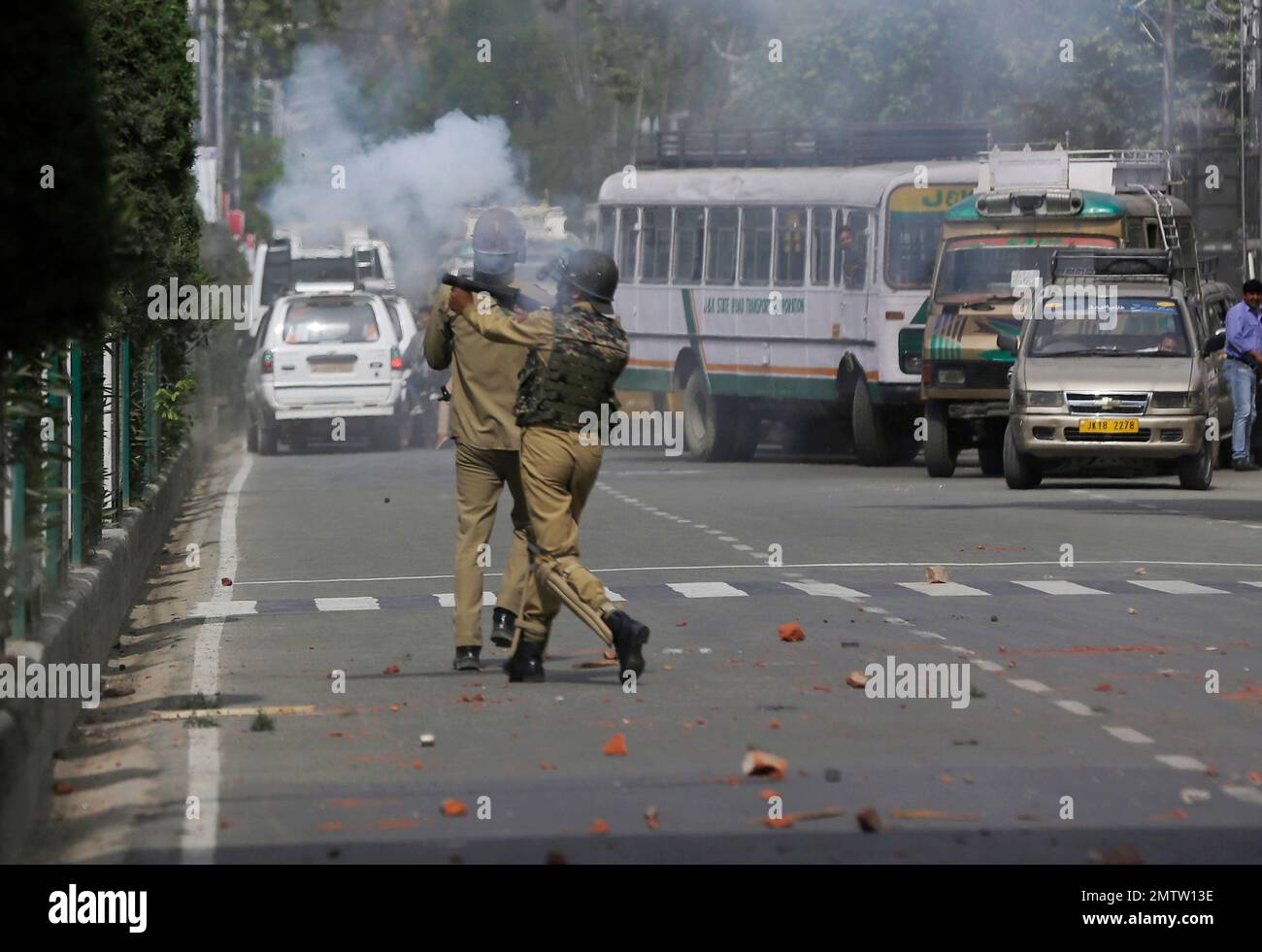 An Indian policeman fires tear smoke shell on protesting Kashmiri ...