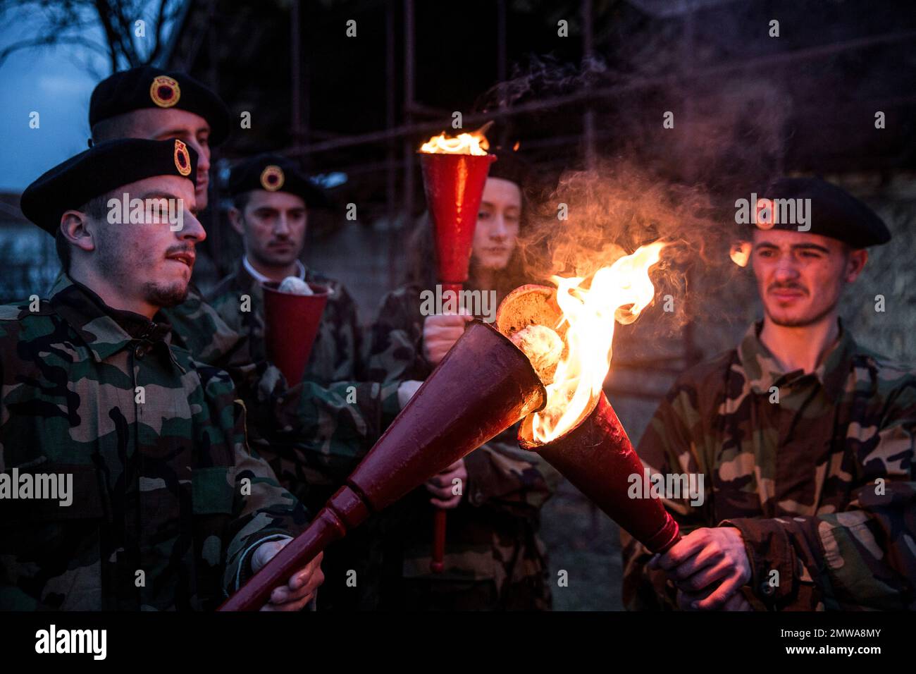 Kosovo Albanians in KLA uniforms light torches during a bonfire ...