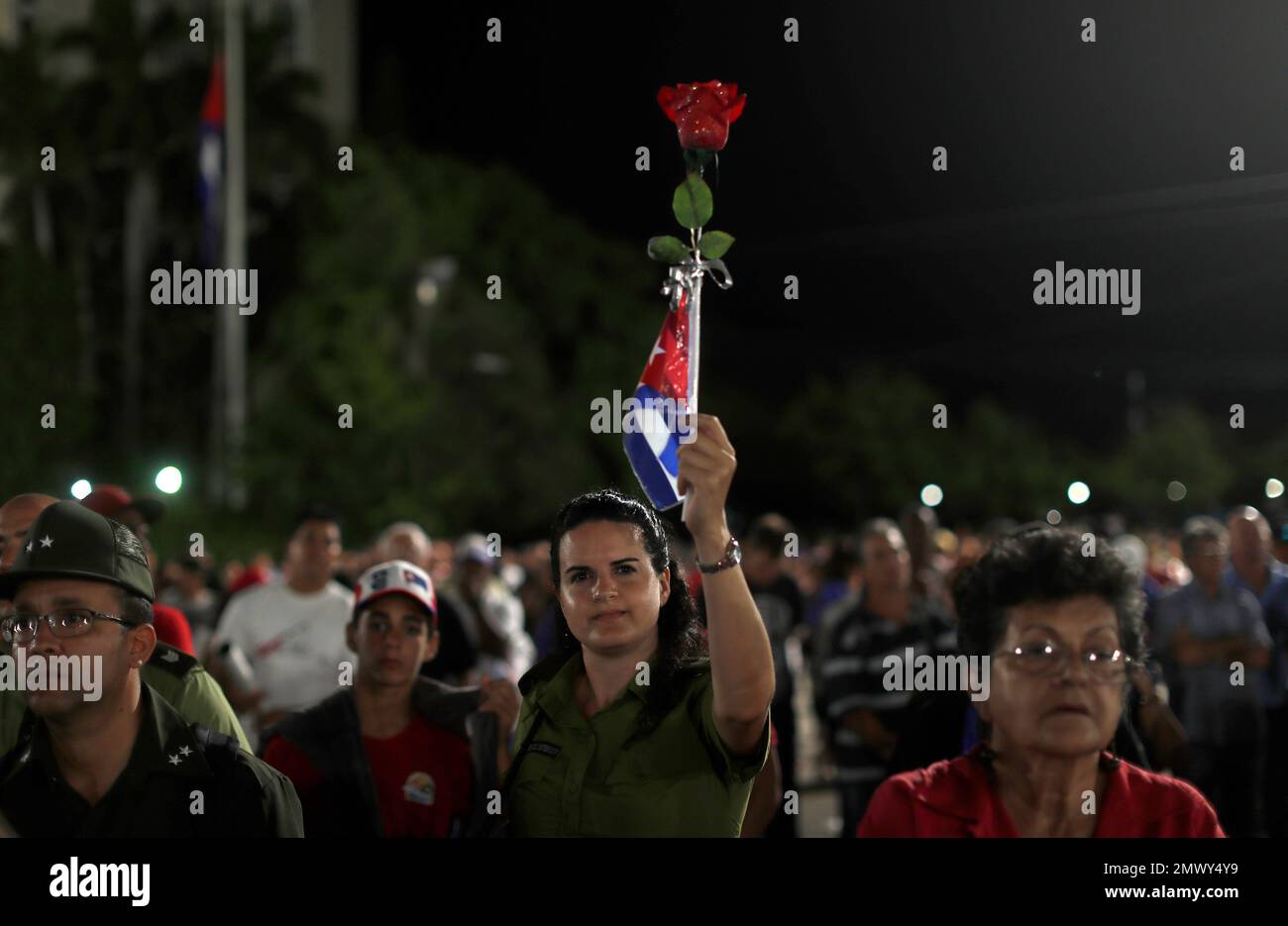 A woman holds up a rose and a Cuban flag during a rally honoring the ...