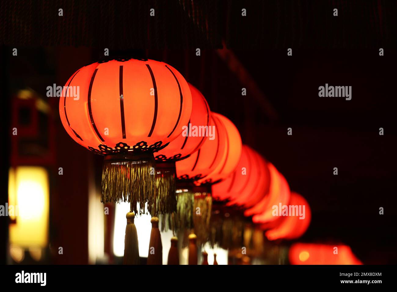 Rote chinesische Laternen leuchten in einer Reihe auf einer Nachtstraße ...