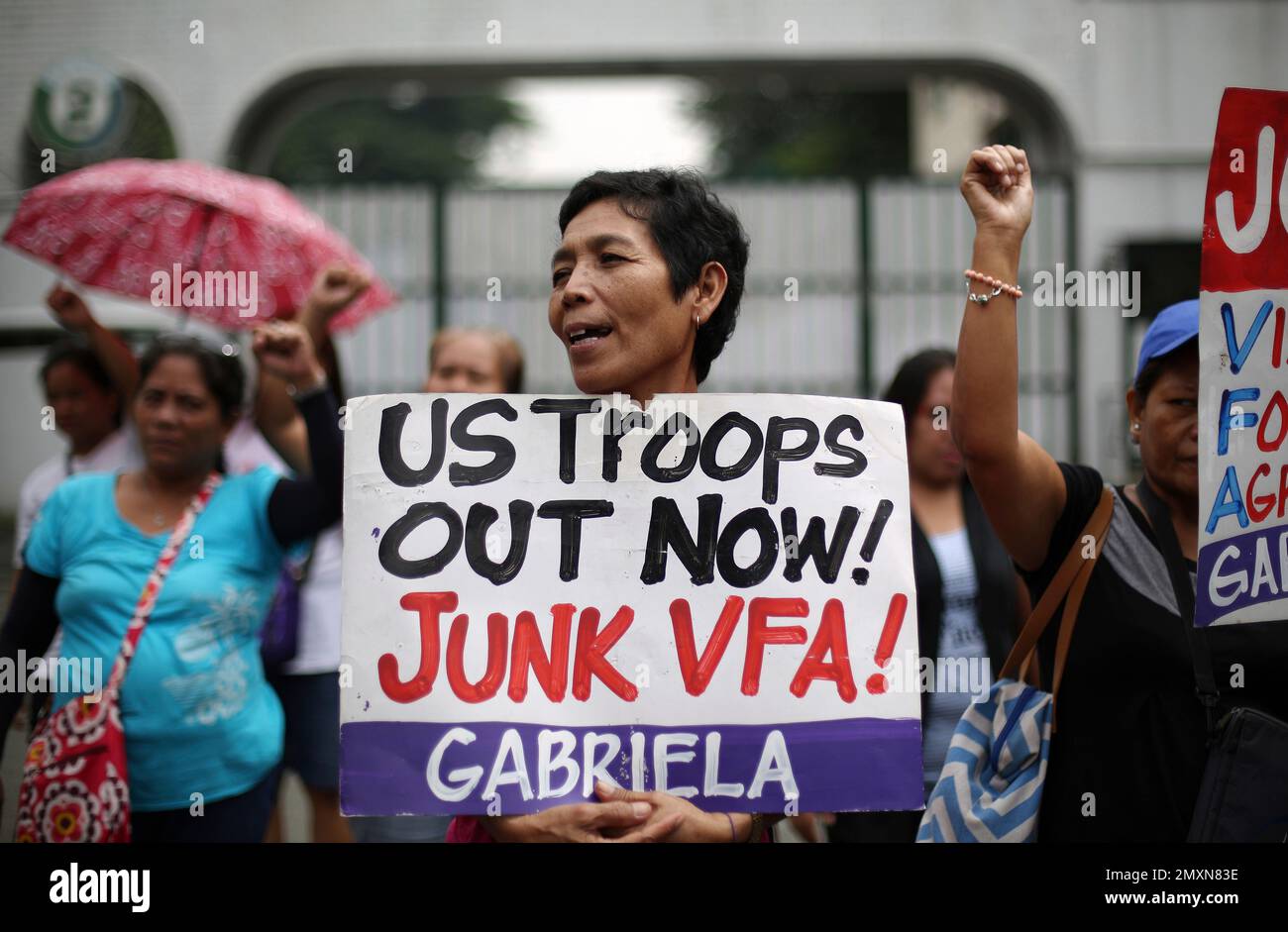 A woman protester shouts slogans with a placard as a group of ...