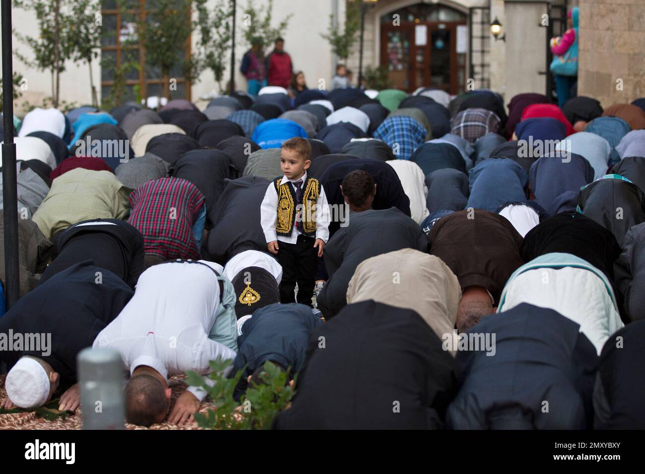 A child looks at Kosovaars praying during Eid al-Adha prayers outside Sultan Mehmet Fatih mosque ...