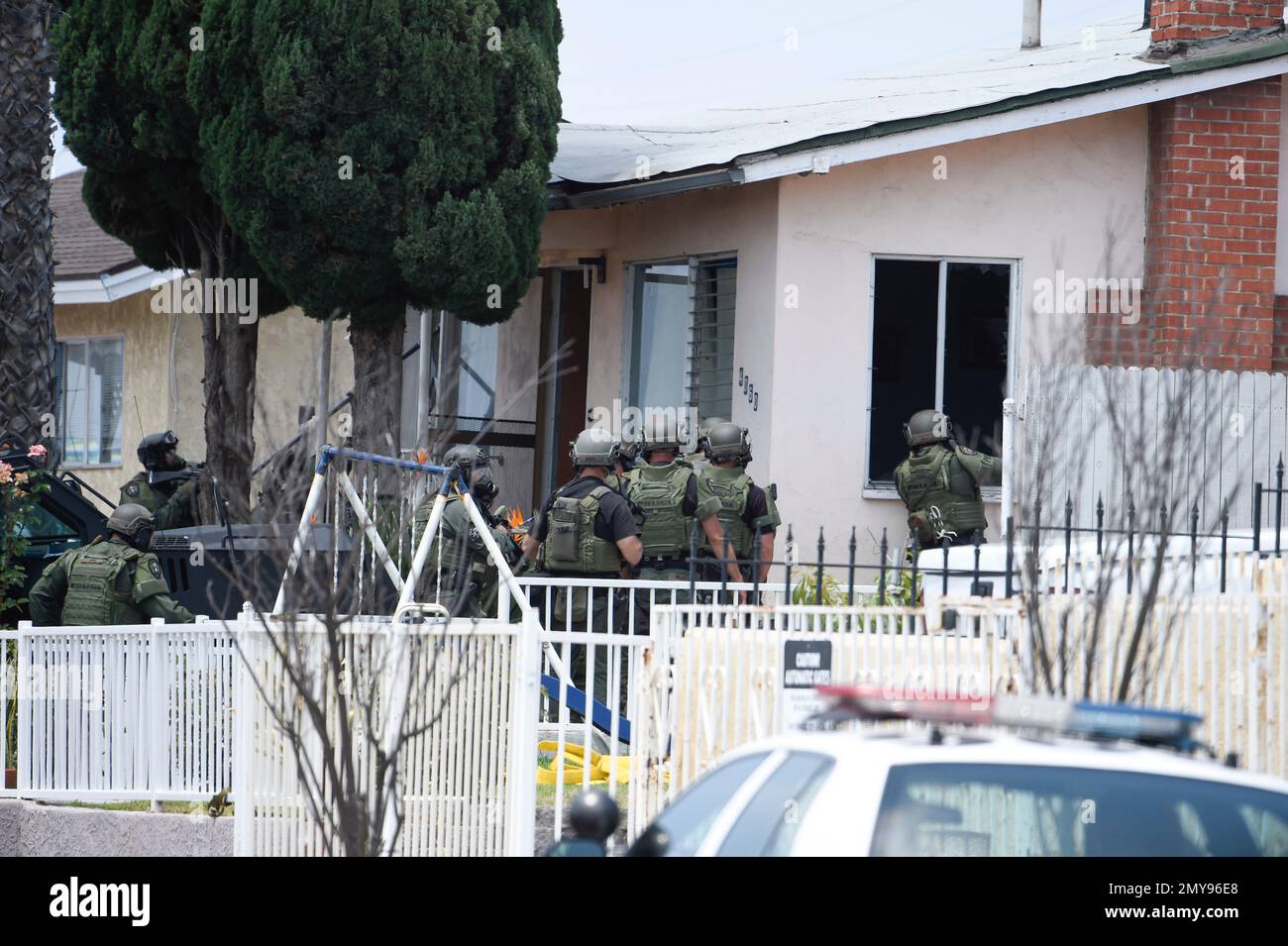 San Diego Police SWAT officers break out windows as they enter a house ...