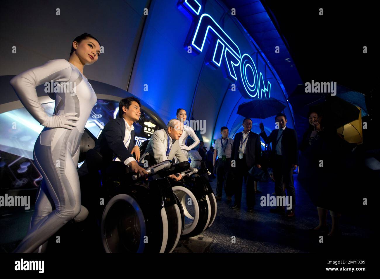 Workers pose for photos with guests outside the TRON Lightcycle Power ...