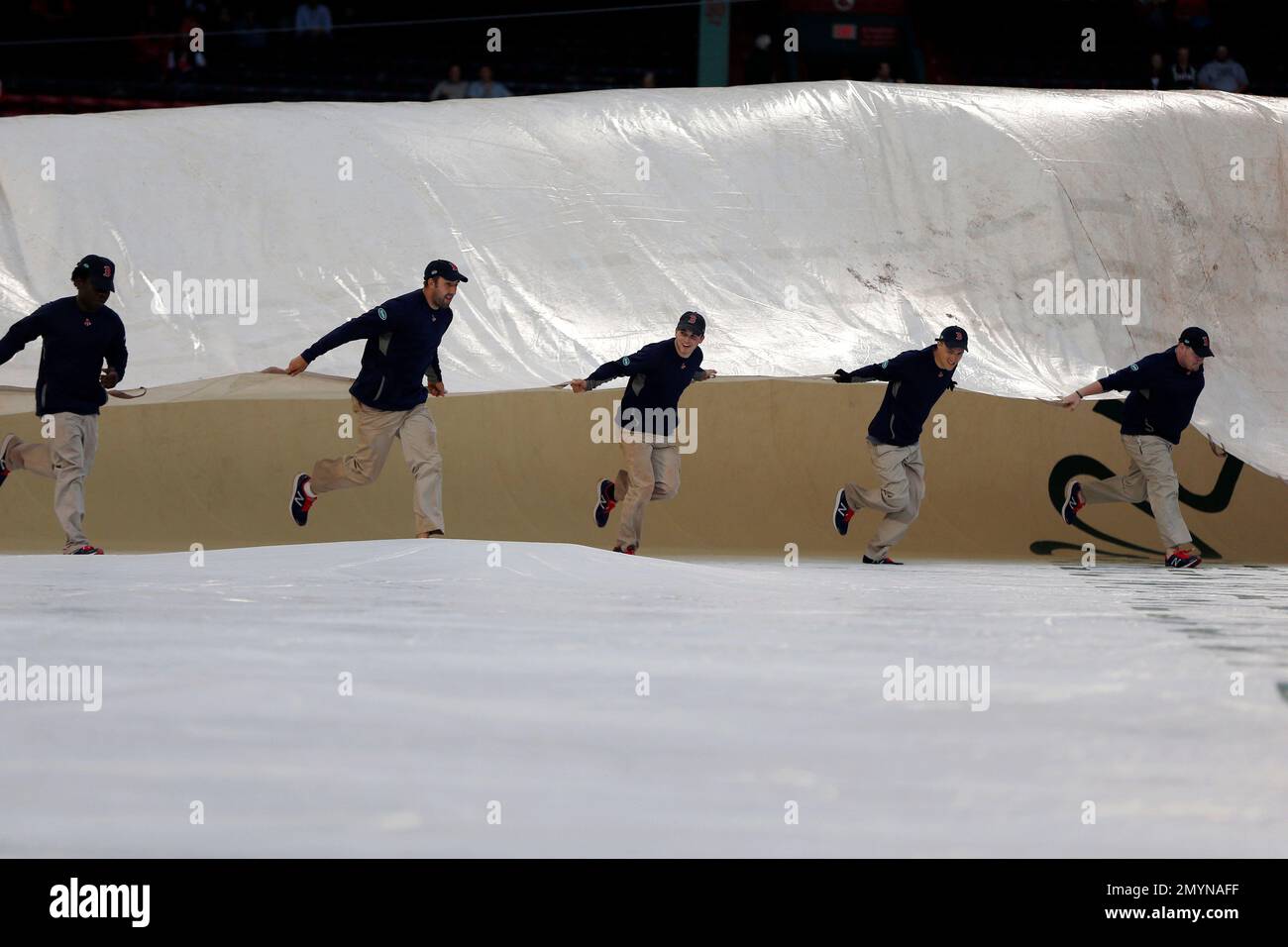 The Fenway Park grounds crew removes the tarp before a baseball game ...