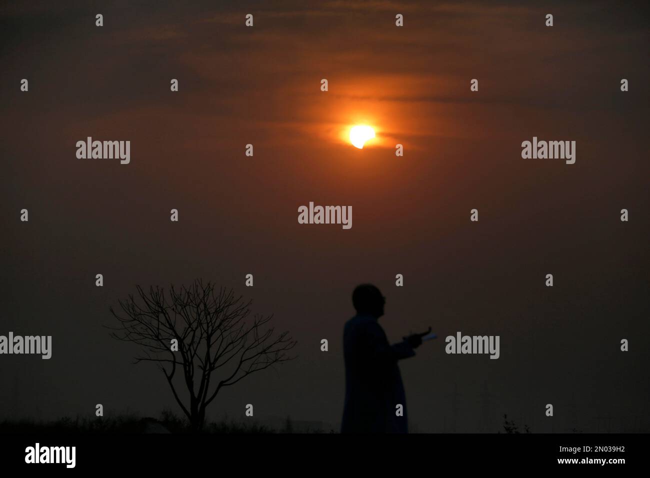 In this March 9, 2016 photo, a Bangladeshi man watches a partial solar eclipse in Dhaka ...