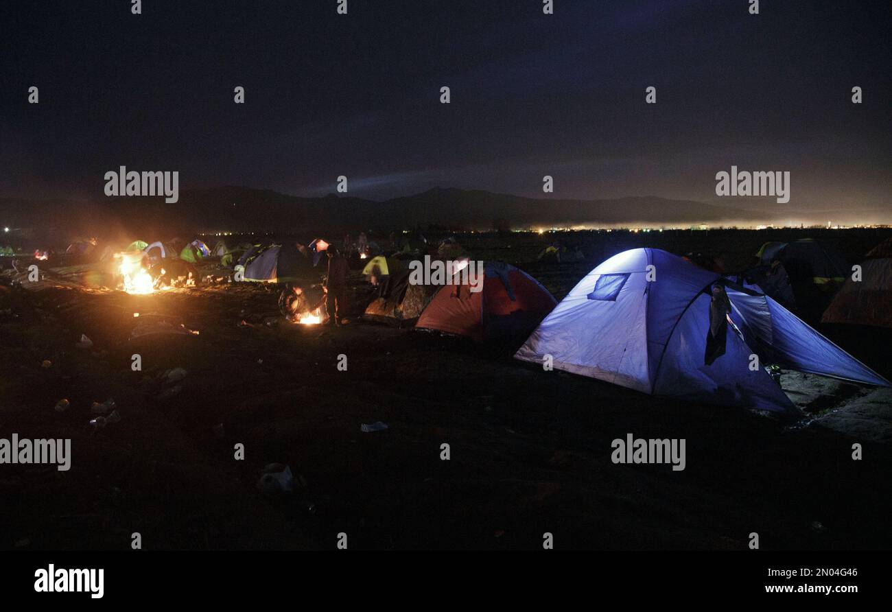 Migrants gather around fire to keep warm close to their tents at the ...