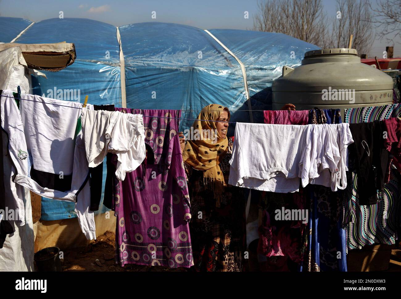 A Syrian refugee woman hangs laundry at a Syrian refugee camp, in the ...