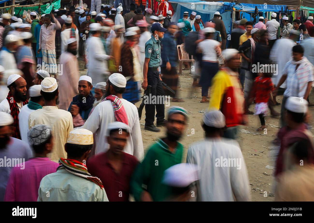 A Bangladeshi policeman stands guard, as Muslim devotees walk past ... A Bangladeshi policeman stands guard, as Muslim devotees walk past ...