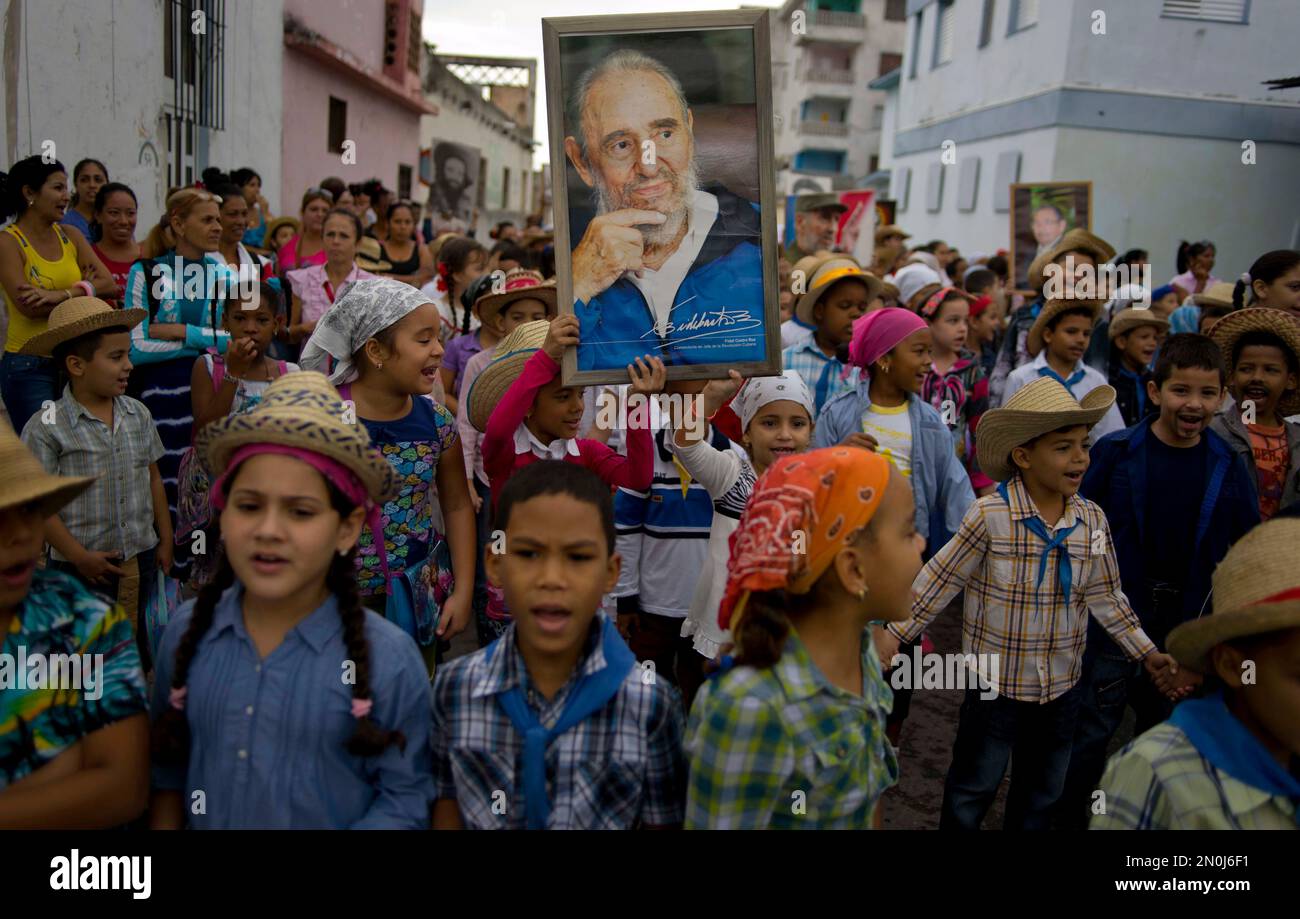 Cuban children, one holding a portrait of Fidel Castro, attend a ...