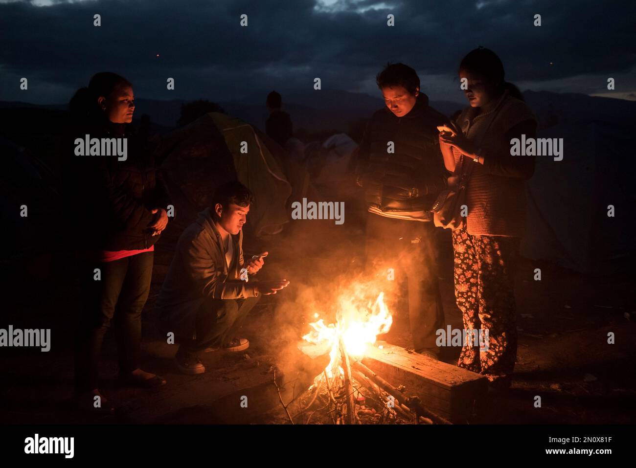 Migrants try to warm up around a bonfire near the northern Greek ...
