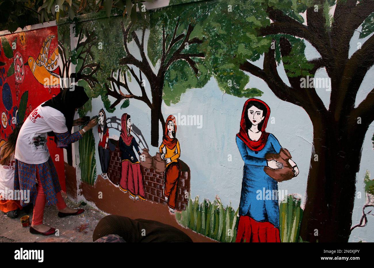 Pakistani students put the final touches to a mural on a wall during a ...
