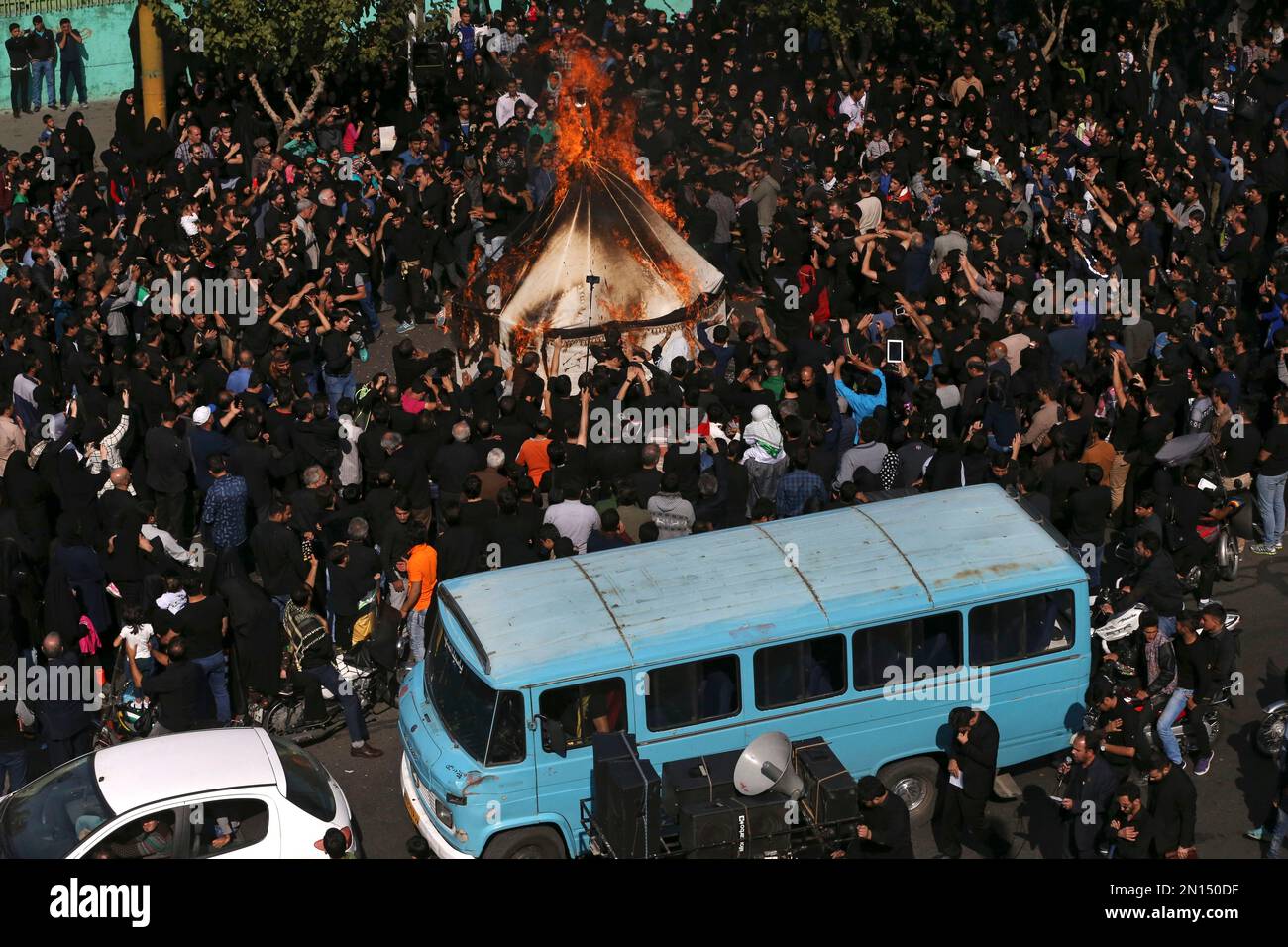 Iranian mourners symbolically beat themselves as they circle a burning ...
