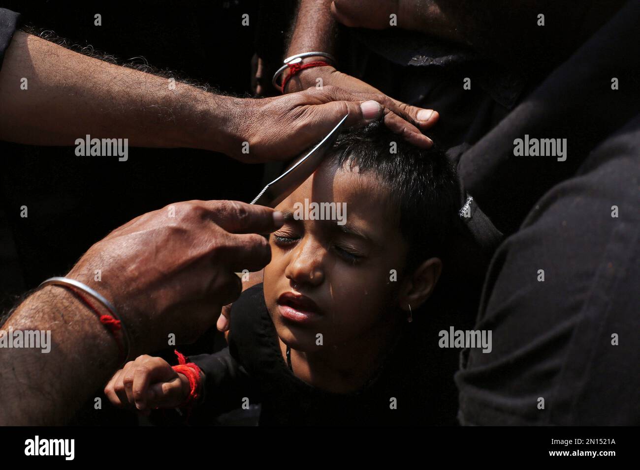 An Indian Shiite Muslim man prepares to make a cut on the forehead of a ...
