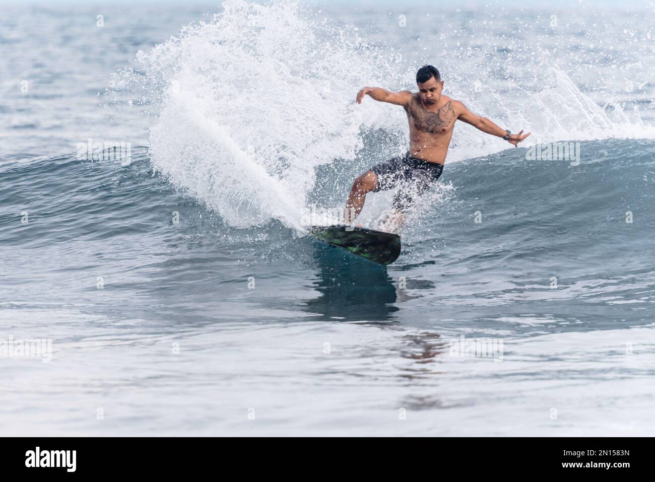 Ein Mann, der mit einem Surfbrett in Keramas Beach, Bali, Indonesien ...