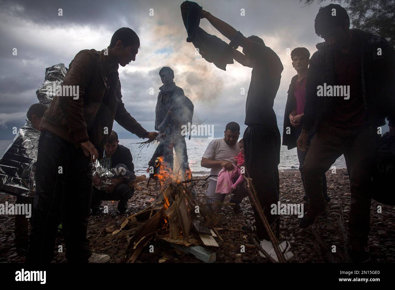 Migrants try to warm up around a bonfire after their arrival from the ...