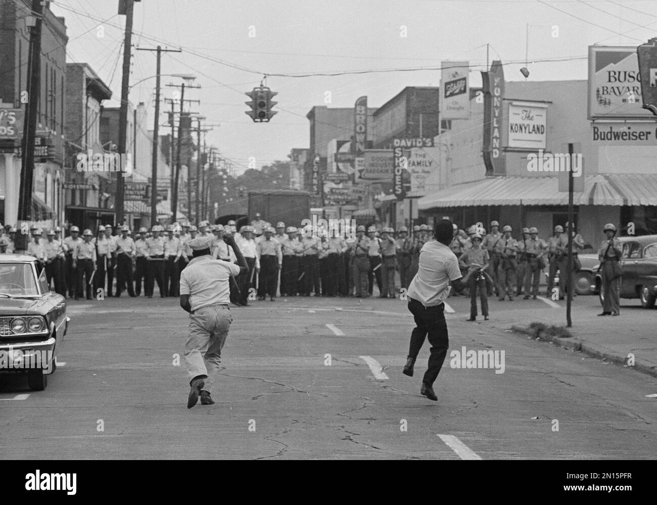 Two black men hurl rocks at a solid line of police who block an ...