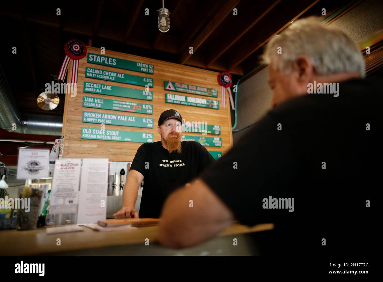 Beer brewer Chuck McLaughlin, background, talks to a client at his ...