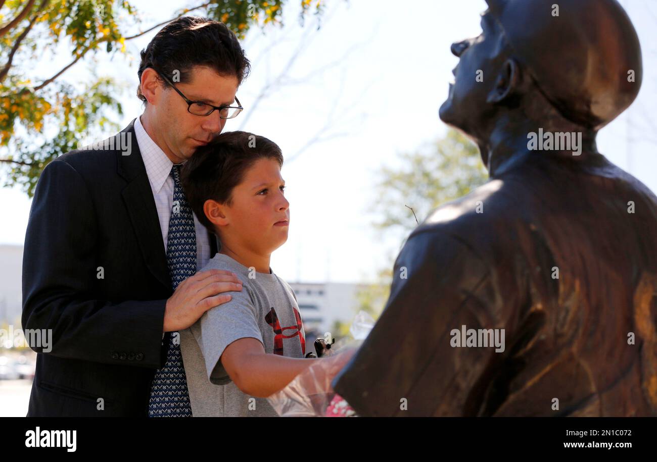 Joshua Raymond, left, holds his son, Max Raymond, 9, while paying their ...