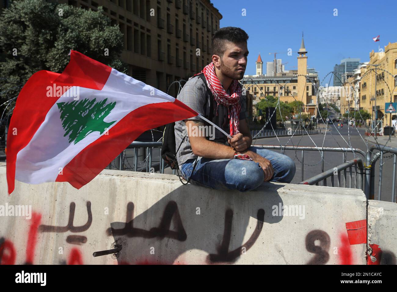 A Lebanese anti-government protester, holds his national flag as he ...