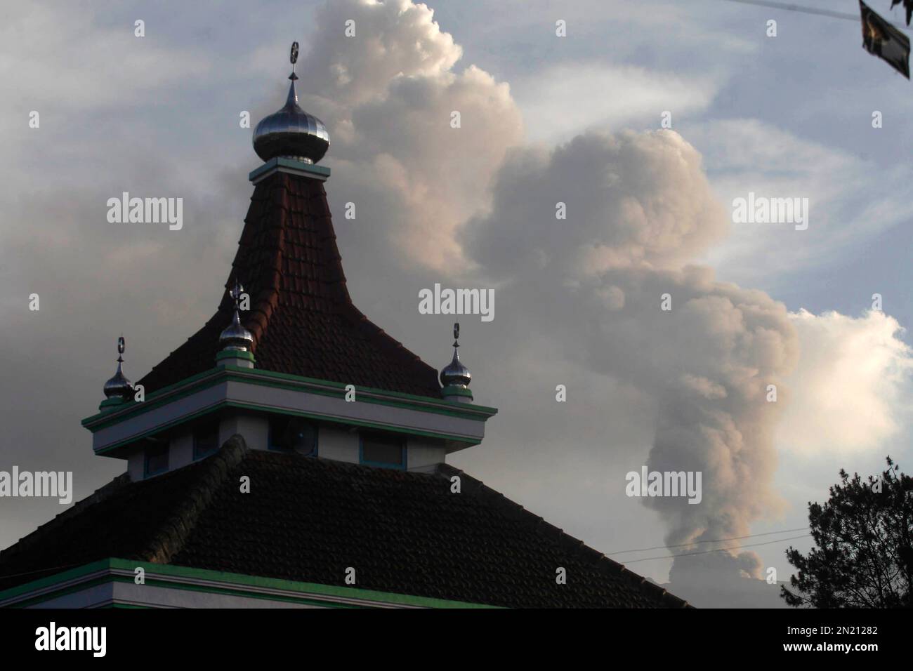 Mount Raung spews volcanic materials into the air with the minaret of a ...