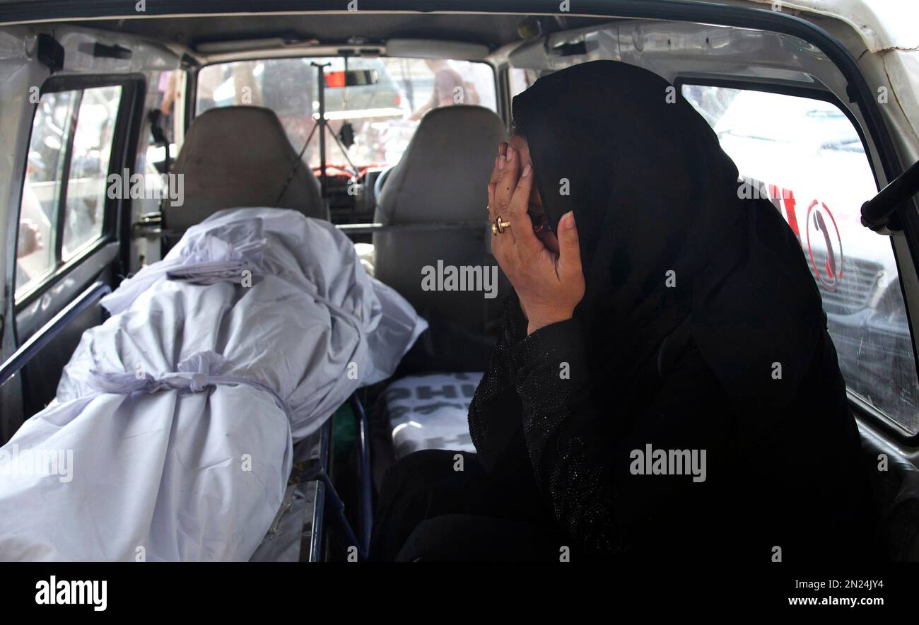 A Pakistani woman mourns as she sits beside the lifeless body of her ...