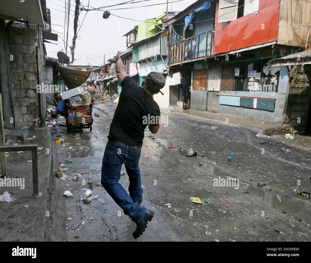 A member of the demolition crew throws a rock at resisting residents ...