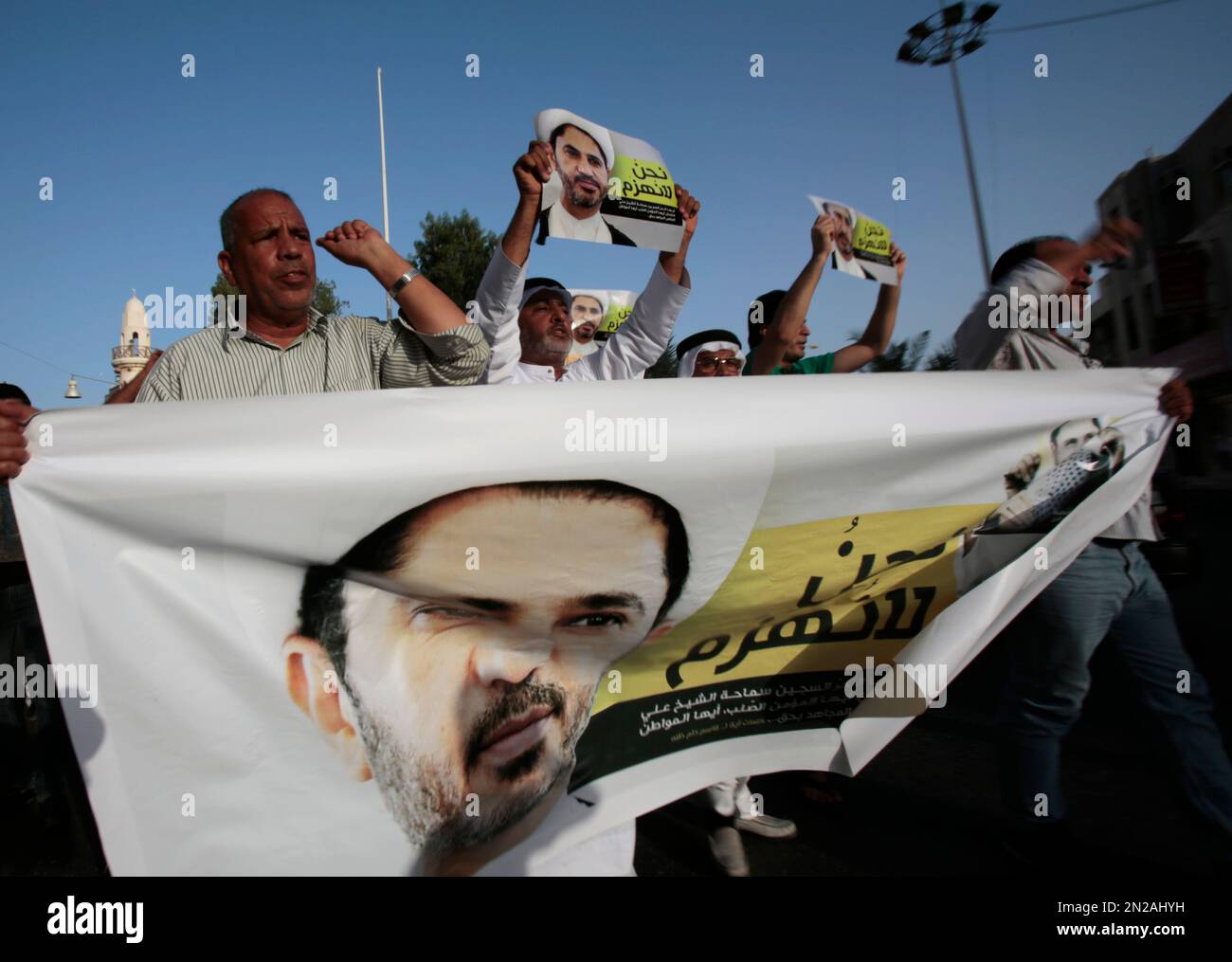 Bahraini anti-government protesters carry a banner and pictures of ...
