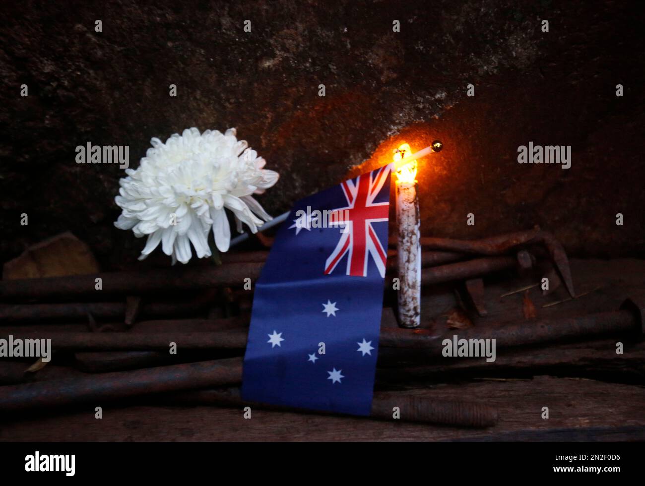 Flower and a candle are laid down next to an Australia nation flag ...