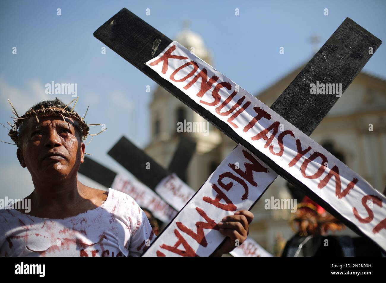 A Filipino man holds a wooden cross with slogans as he and others ...