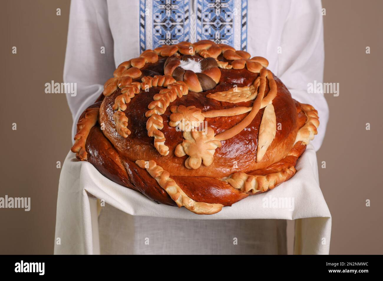 Frau mit Korovai auf grauem Hintergrund, Nahaufnahme. Ukrainisches Brot ...