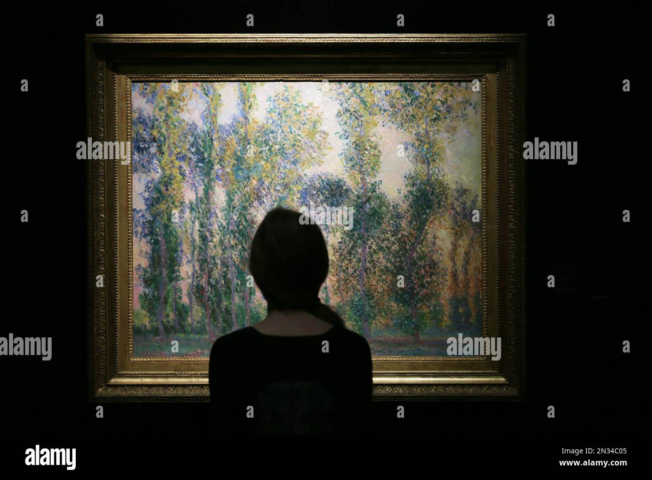 A girl poses for a picture with 'Les Peupliers a Giverny' by Claude ...