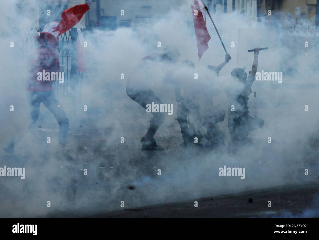 Bahraini anti-government protesters holding national flags duck behind ...