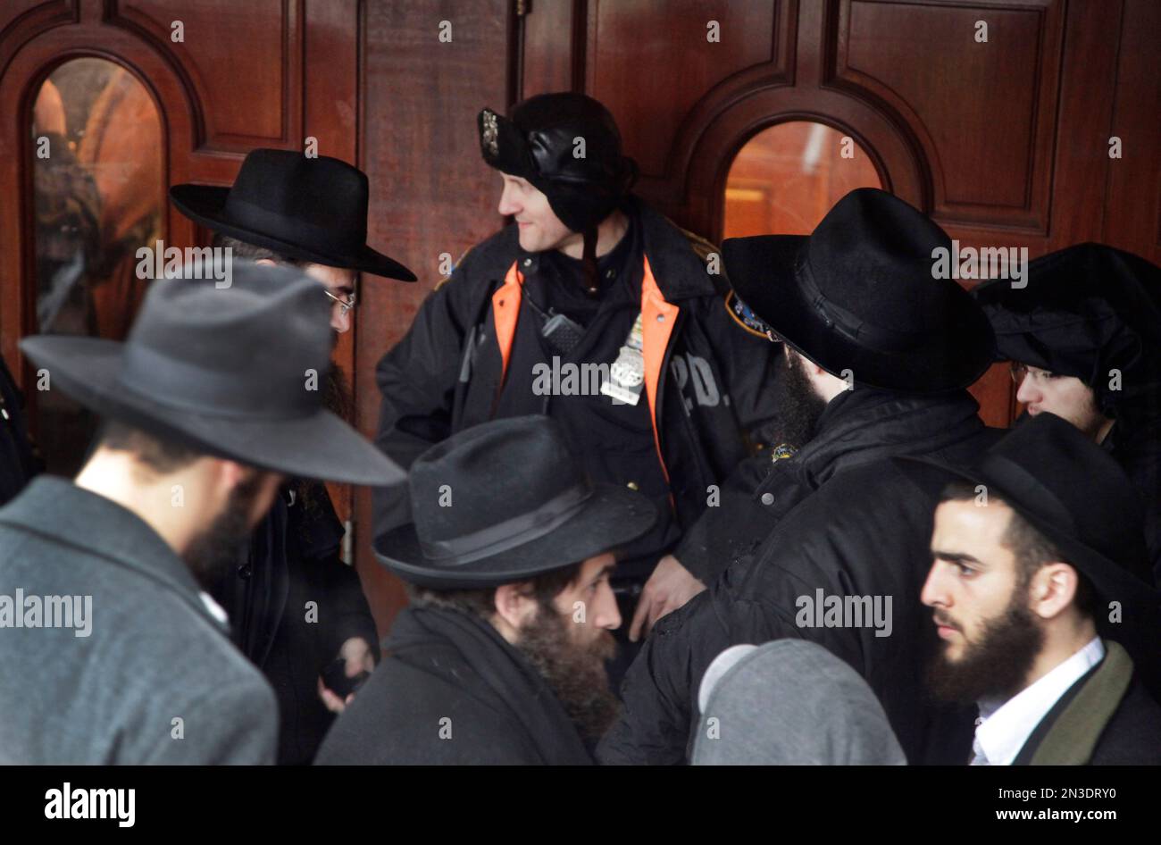 A New York City police officer, center, stands guard outside Chabad ...