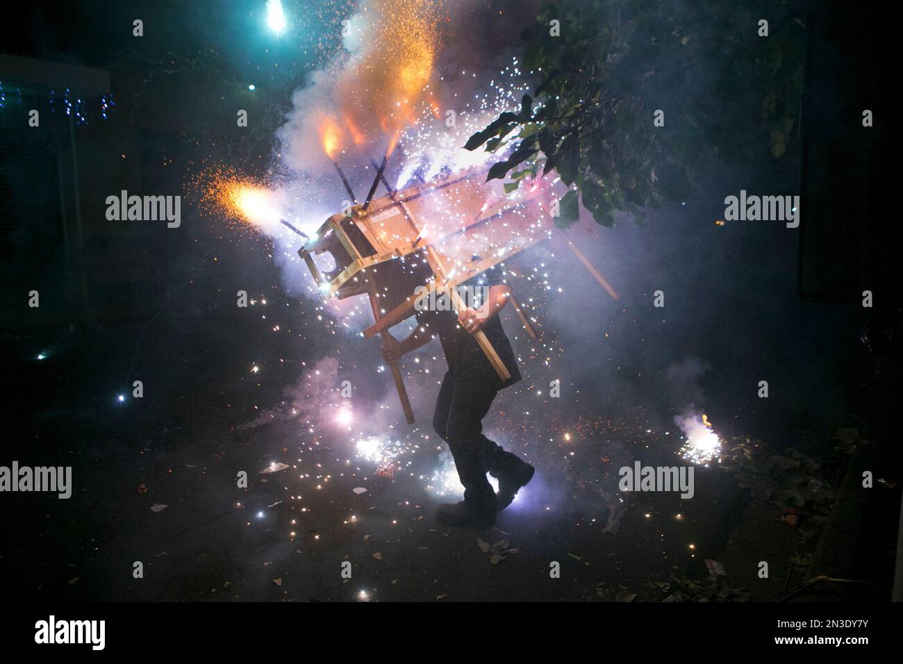 A man runs with a "toro encuetado," a structure resembling a bull and ...