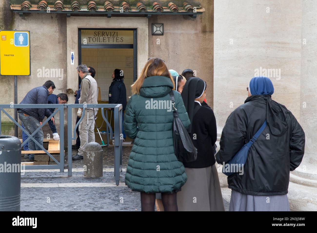 Workers, left, stand as people queue outside the public restrooms off ...