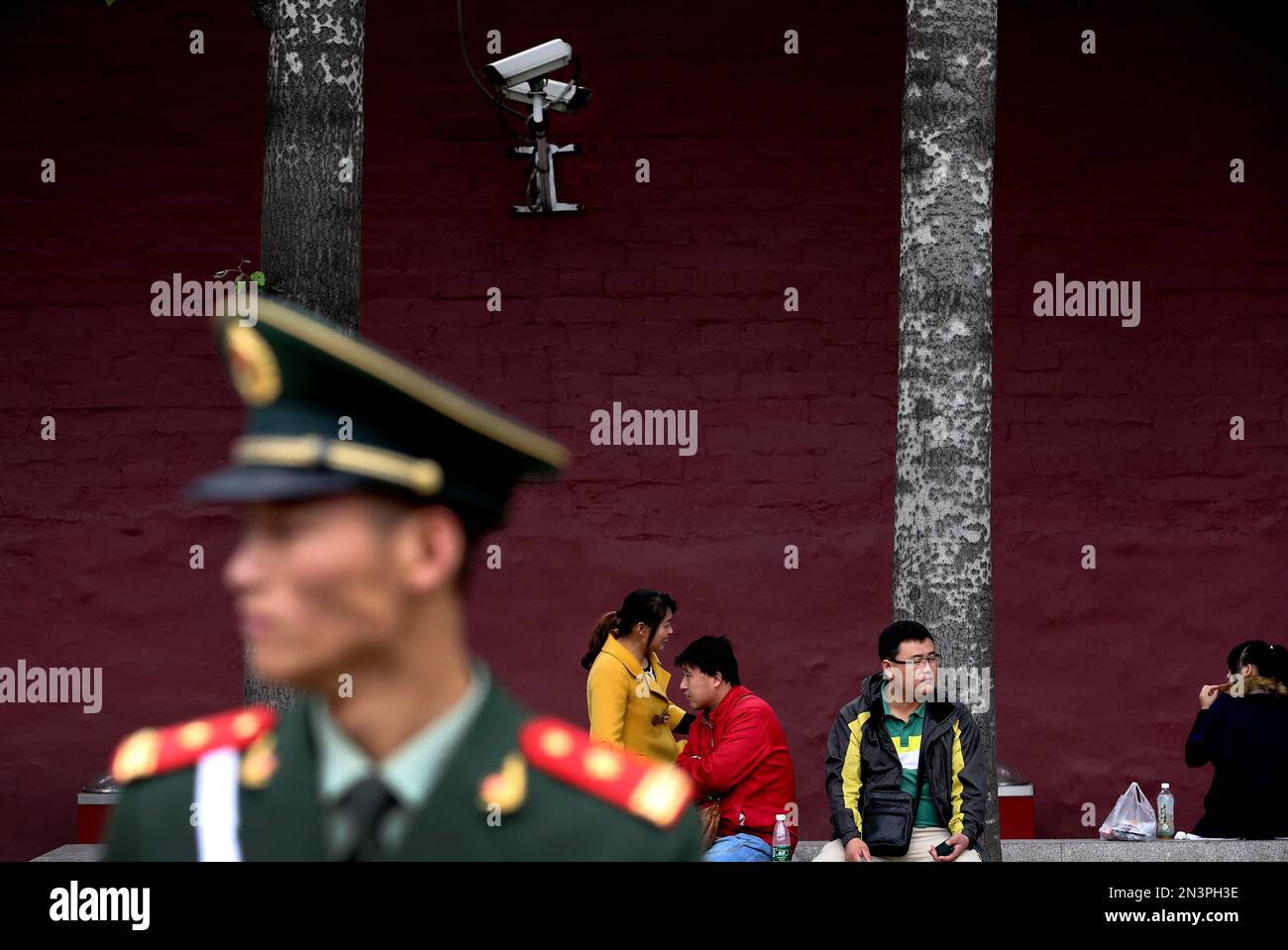A Chinese paramilitary policeman stands watch as people take a rest ...