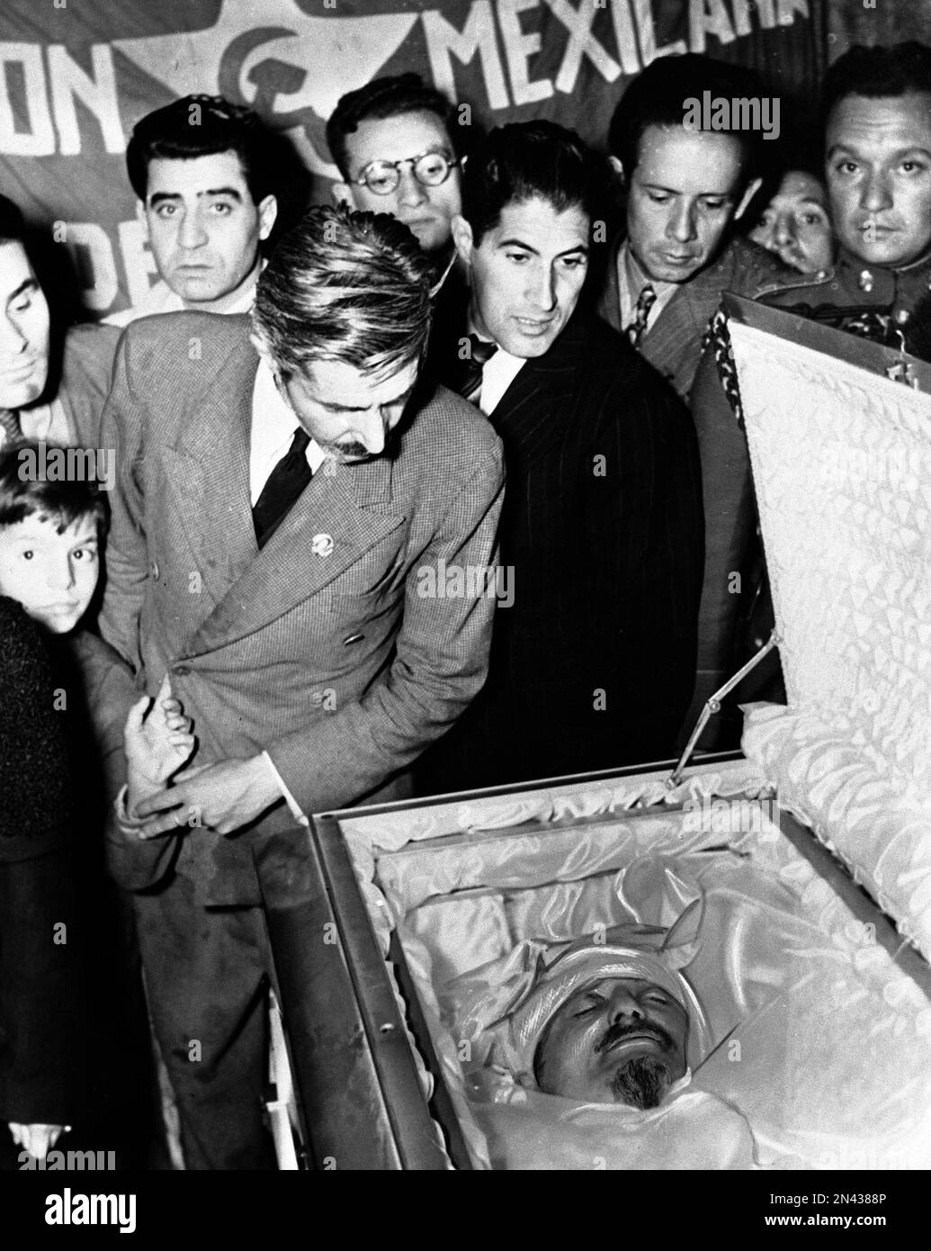 A long line of mourners and curious pass the open casket of Leon ...