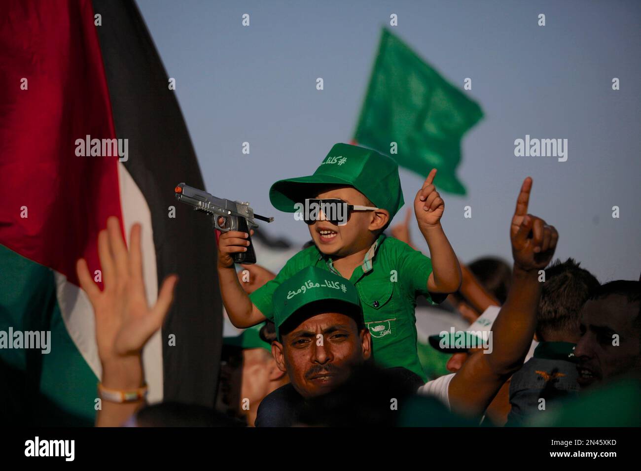 A boy sits on his father shoulders as he carries a toy gun during a ...