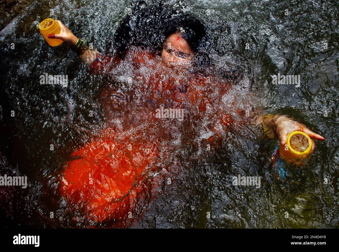 A Hindu devotee takes holy dip as she collects holy water from the ...