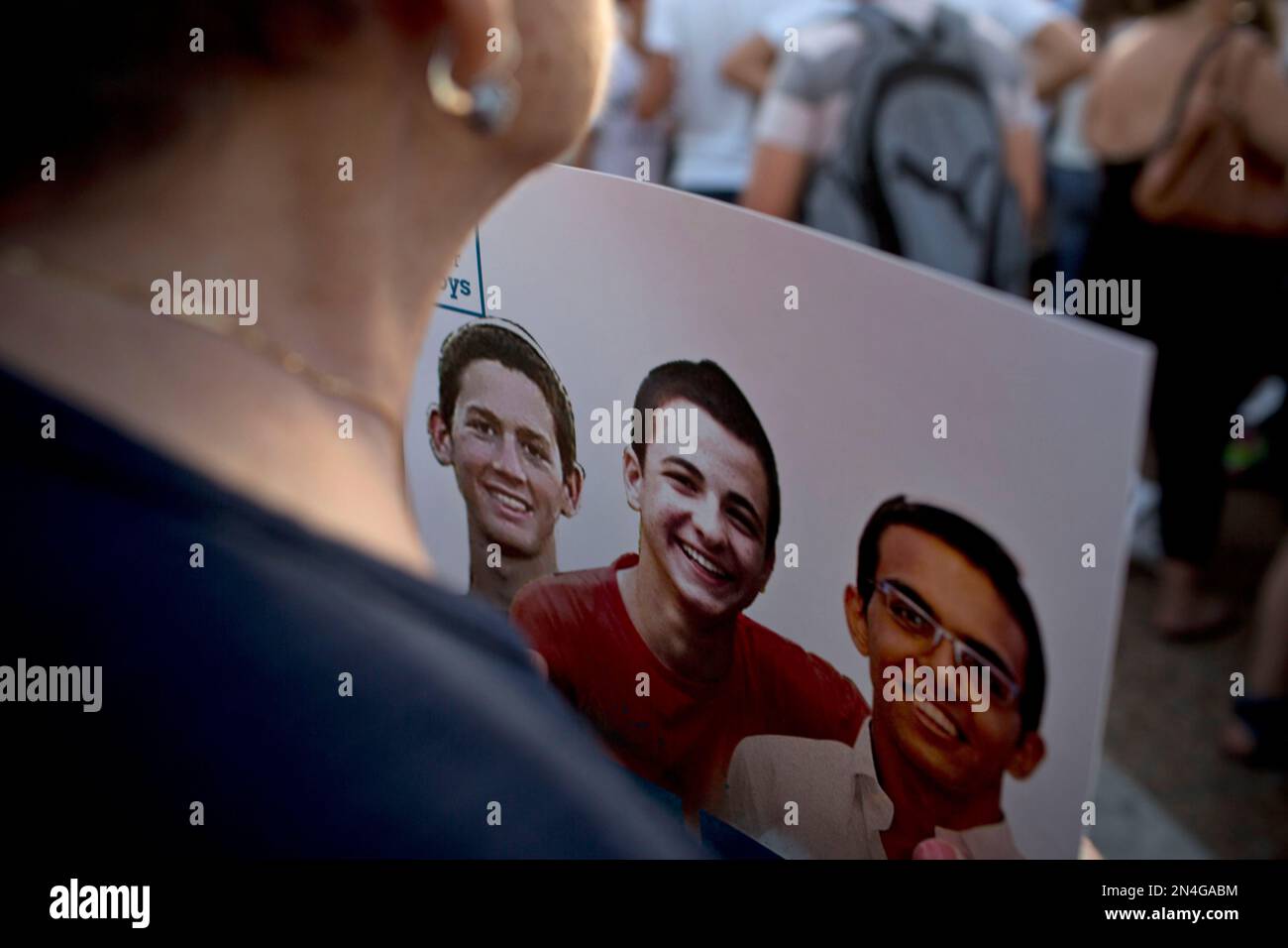 An Israeli woman holds a poster with photos of the three missing ...