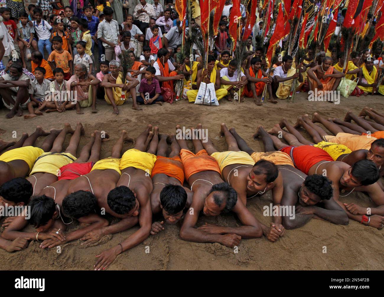 Indian villagers lie down on hot sand as part of a ritual as they ...