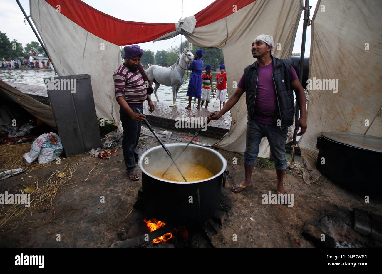 Sikh devotees prepare food at a community kitchen while a Nihang or a ...