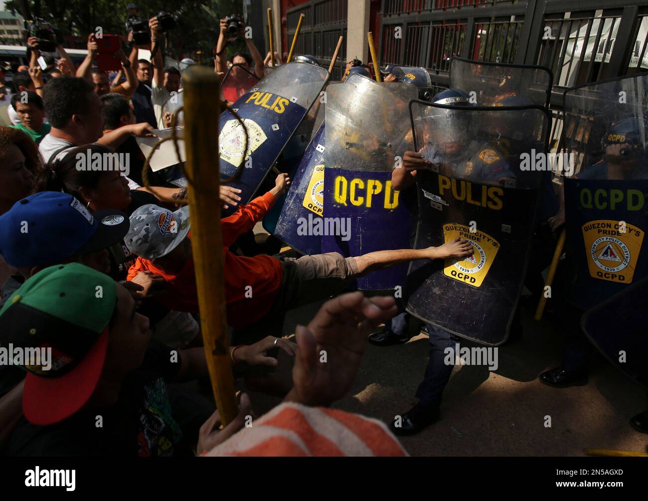 A Filipino protester kicks the shield of riot police as they tried to ...