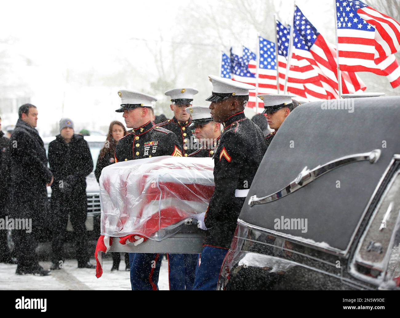 A U.S. Marine Honor Guard carries the casket containing the body of ...