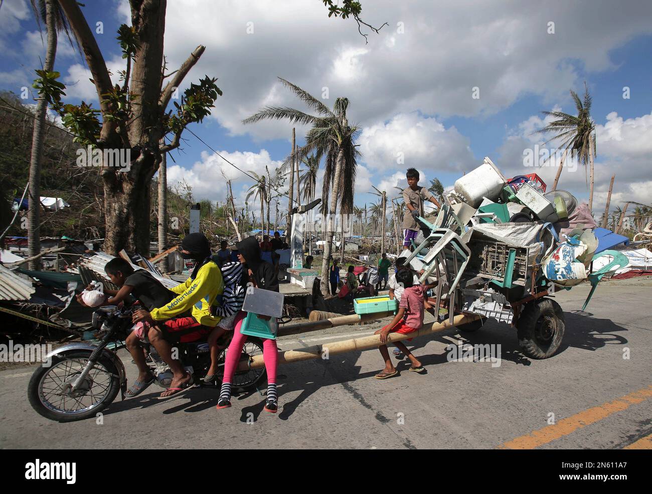 Typhoon survivors pull a cart full of used plastic wares at typhoon ...