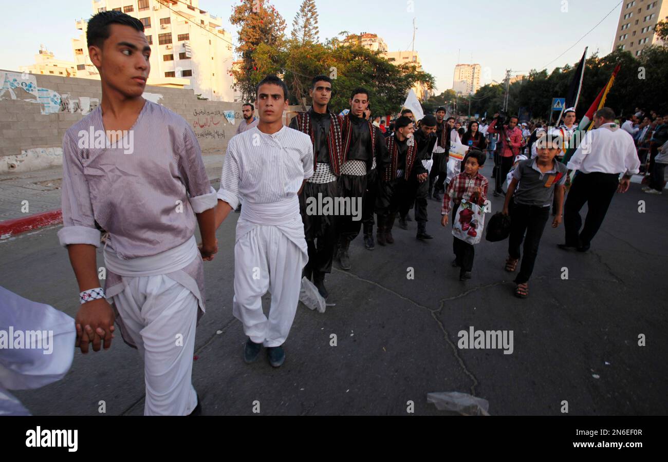 Palestinian men dressed in traditional attire perform a traditional ...
