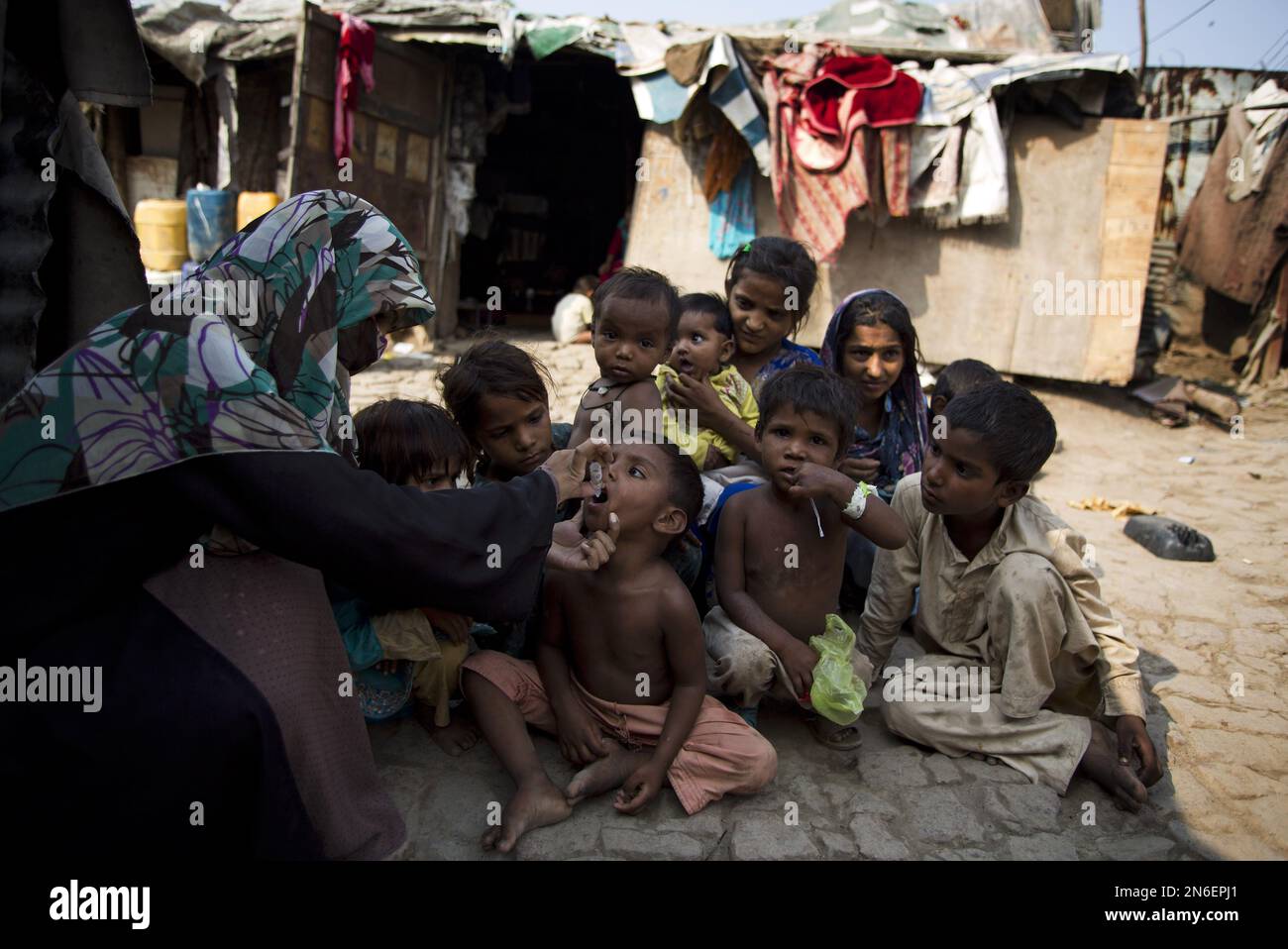 A Pakistani health worker administers polio vaccine to children in a ...