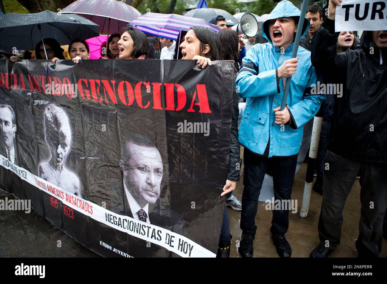 Protestors with a banner that reads in Spanish "genocide" and has a ...