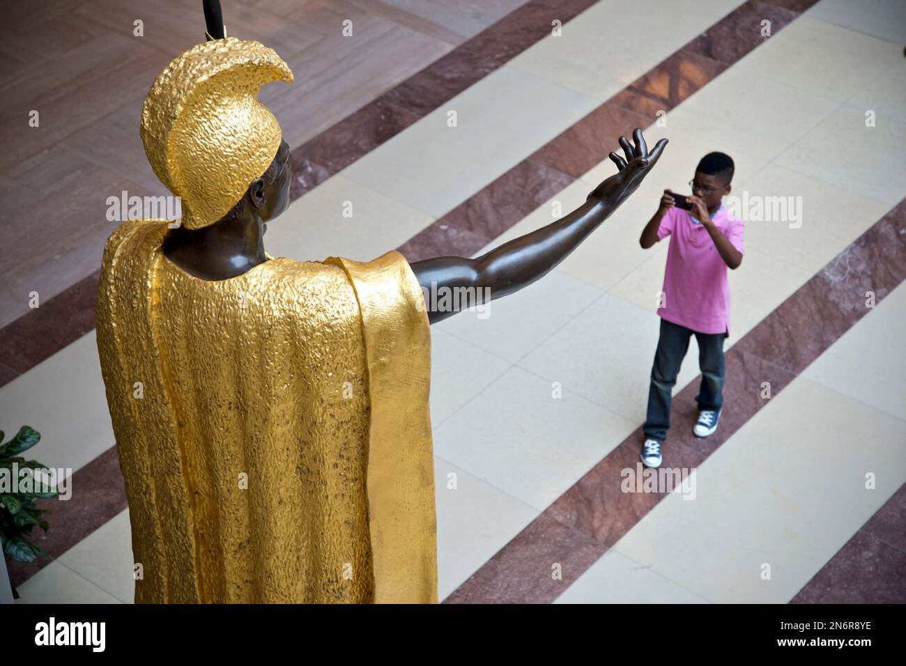 A young tourist snaps a photo beneath the towering bronze statue of ...
